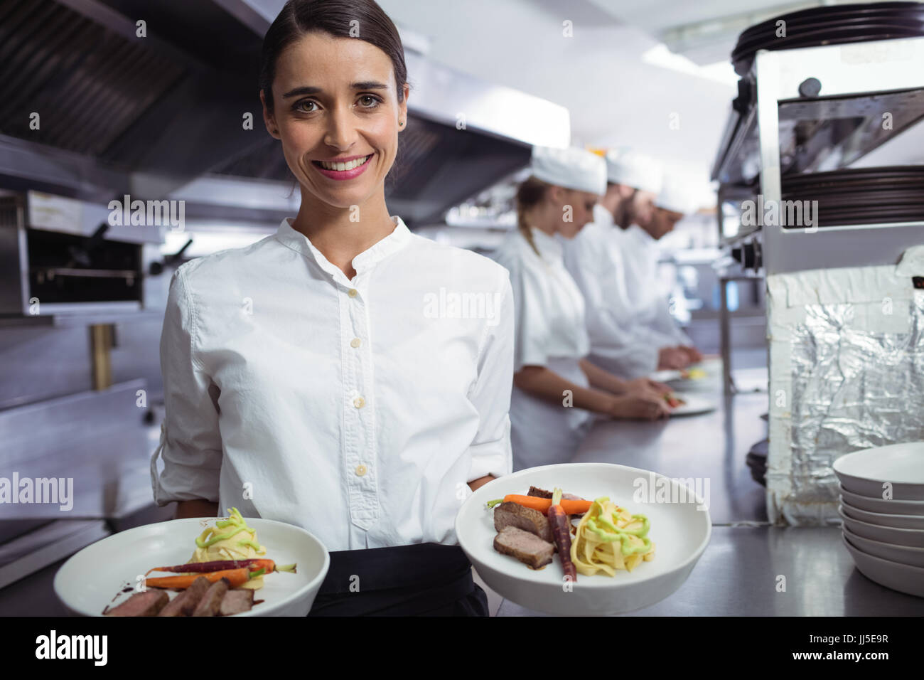 Portrait of chef presenting his food plates in the commercial kitchen ...