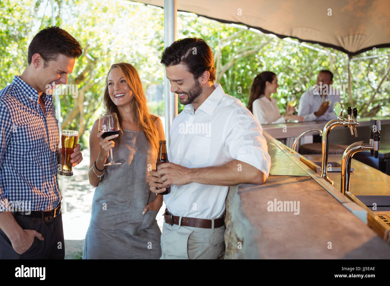 Smiling friends interacting while having a alcohol at counter Stock ...