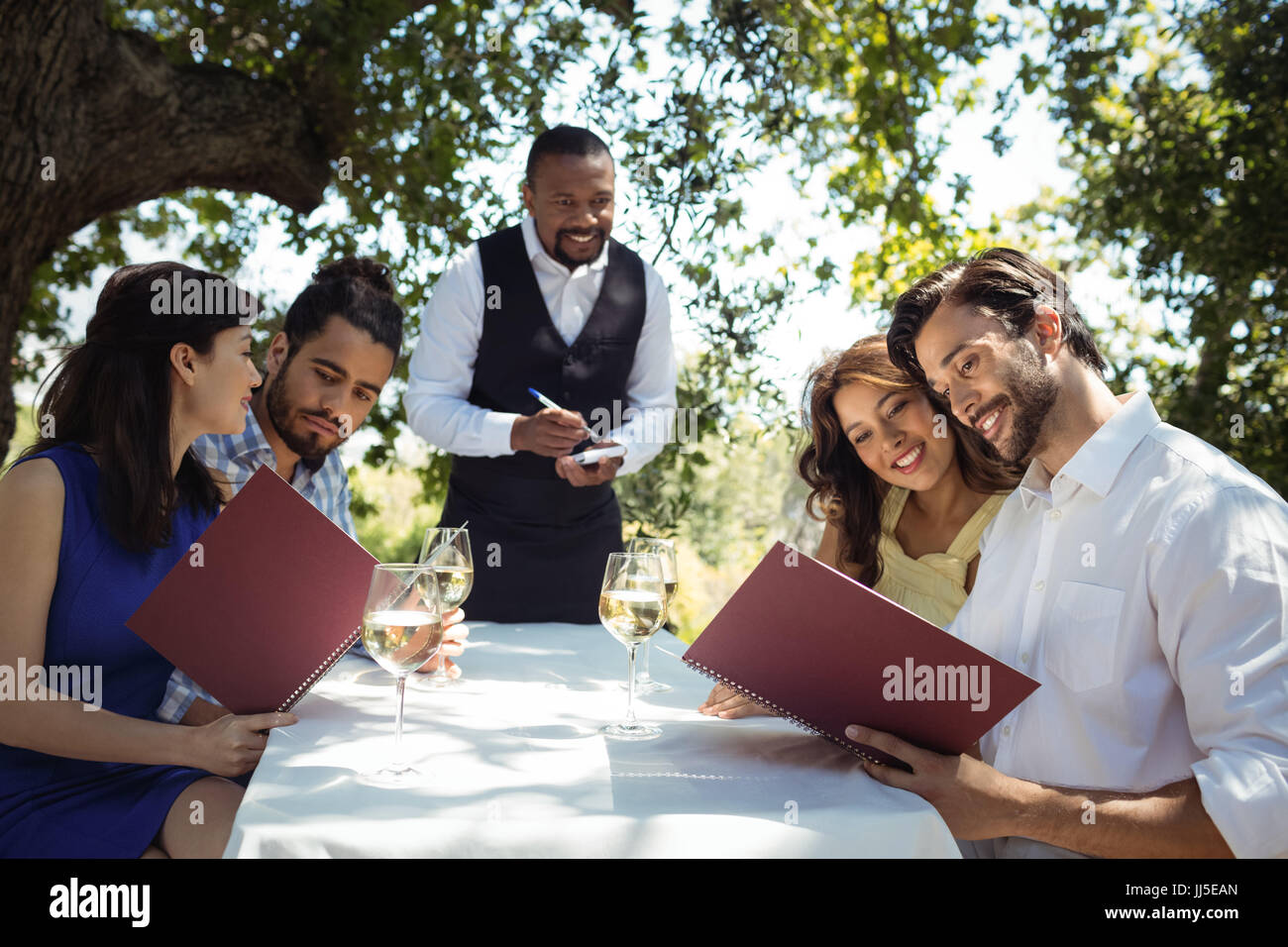 Friends placing order to waiter in restaurant Stock Photo - Alamy