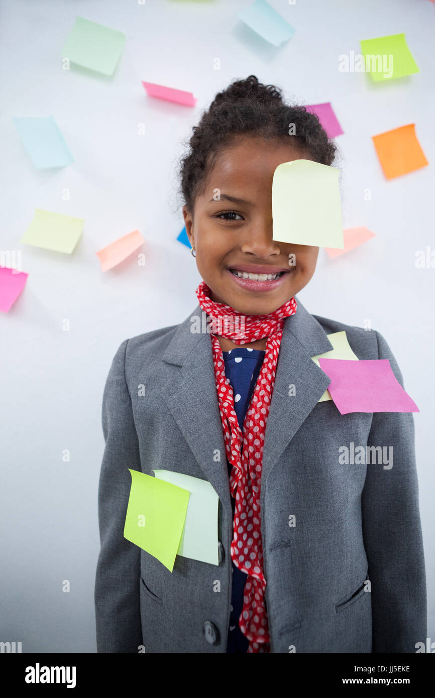 Happy businesswoman with sticky notes stuck on suit and head standing ...