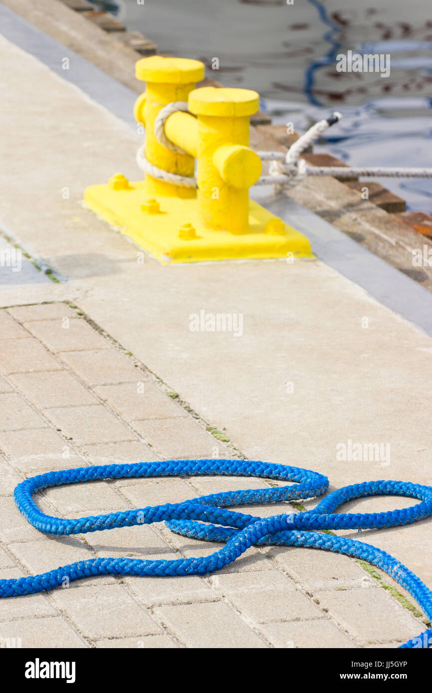 Blue rope and yellow mooring bollard in background, closeup and detail ...