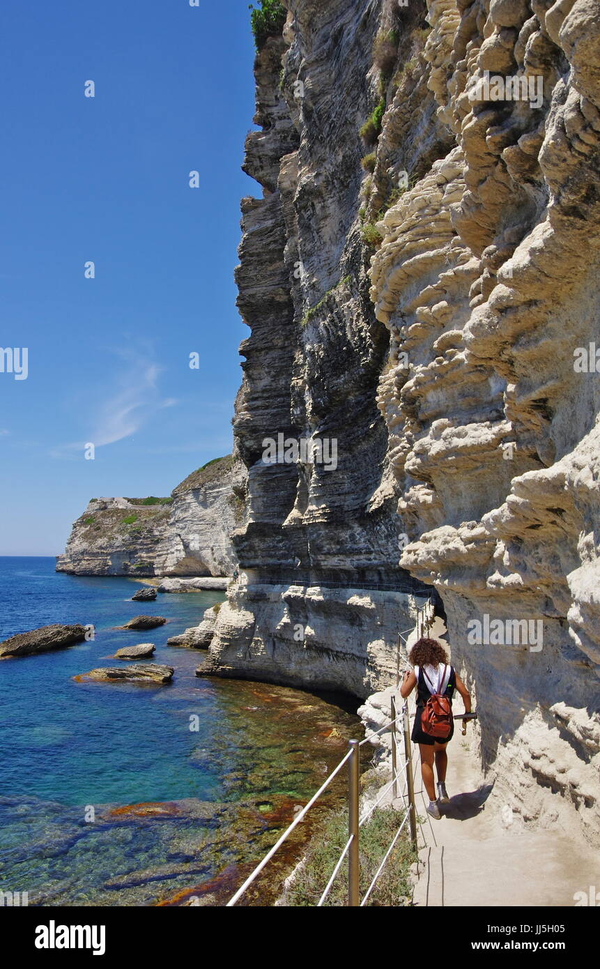 Young female tourist on the narrow path carved in the cliffs below ...