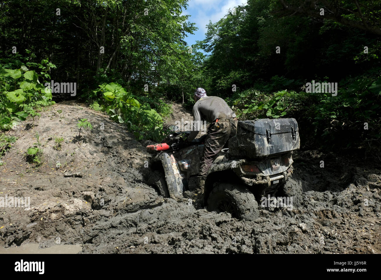 A Russian man rides an all-terrain quad bike vehicle ATV in a muddy ...