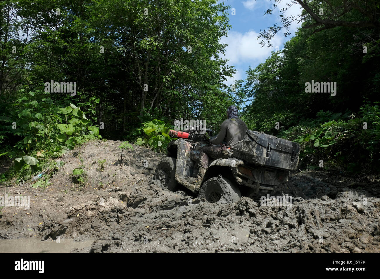 A Russian man rides an all-terrain quad bike vehicle ATV in a muddy ...