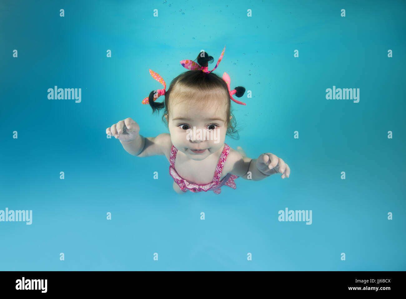 little girl In a pink swimsuit dives in the swimming pool Stock Photo ...