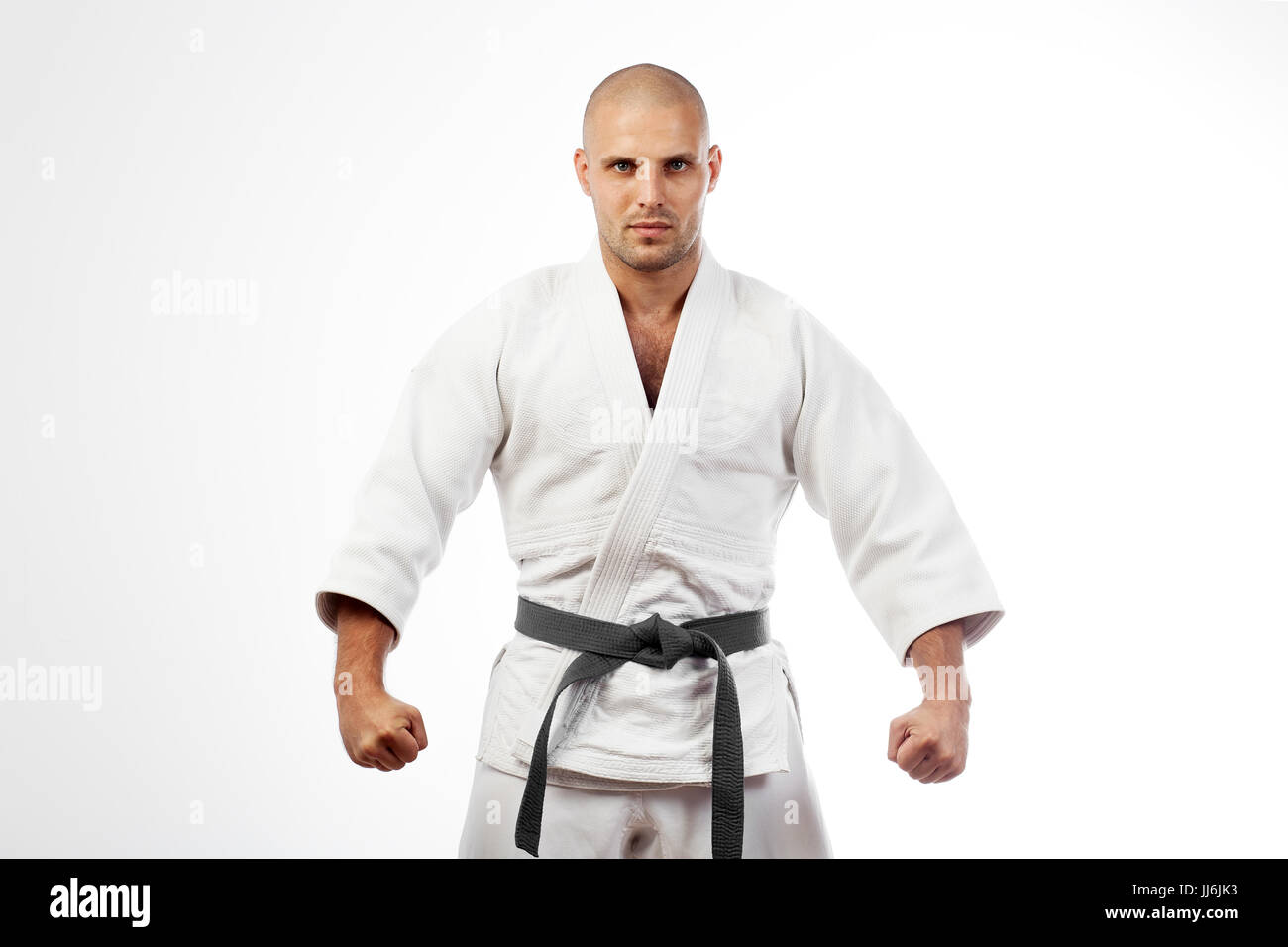 Young athletic man in white kimono for sambo, judo, jujitsu posing on ...