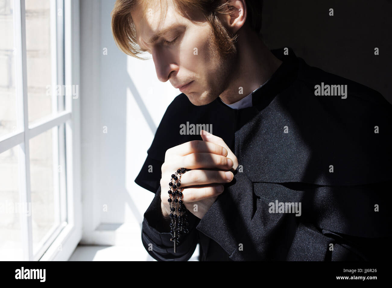 Portrait of handsome young catholic priest praying to God Stock Photo ...