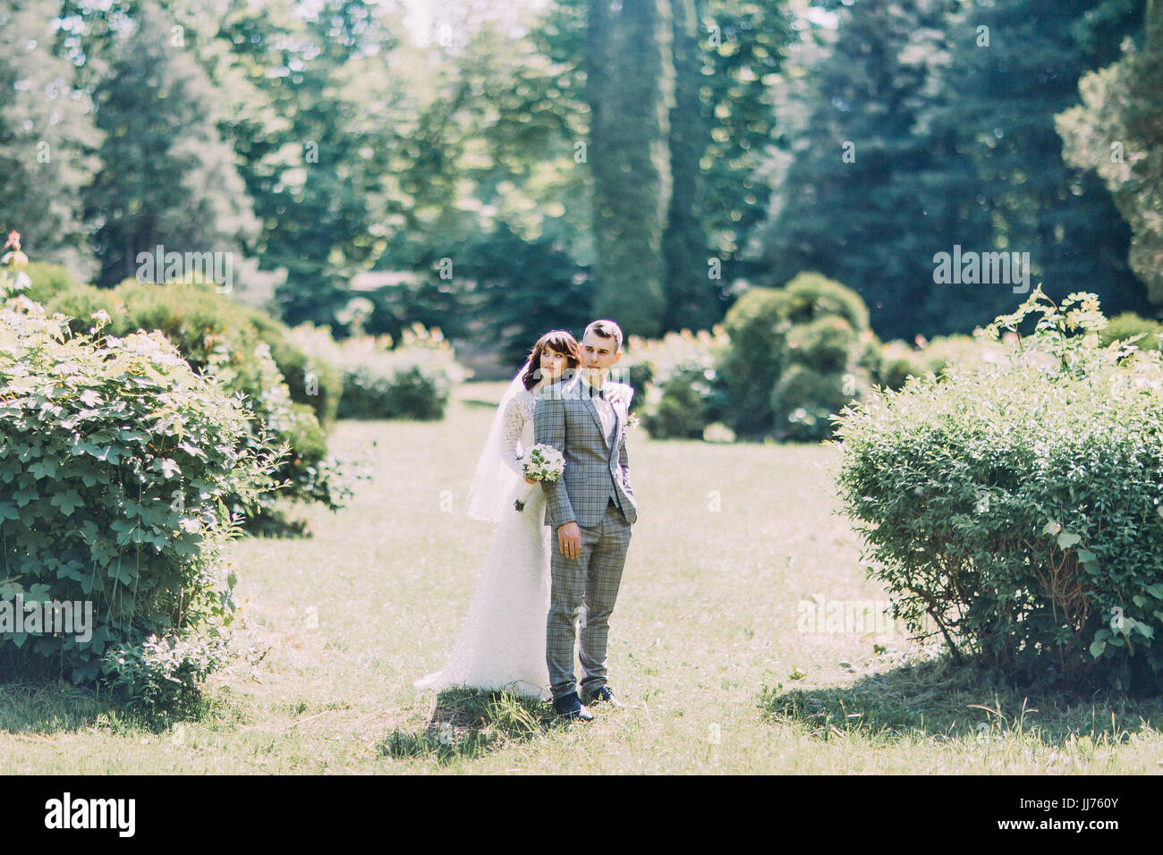 The full-length horizontal view of the bride hugging the groom back in ...