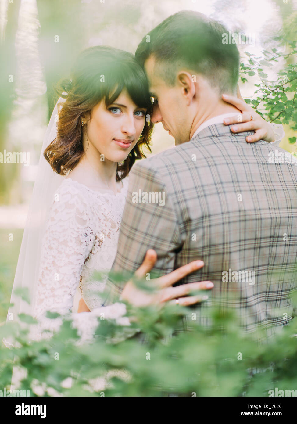 The close-up back view of the groom hugging the beautiful bride among ...