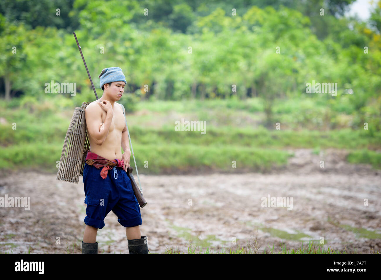 Male farmer carrying a rifle walks along Stock Photo - Alamy