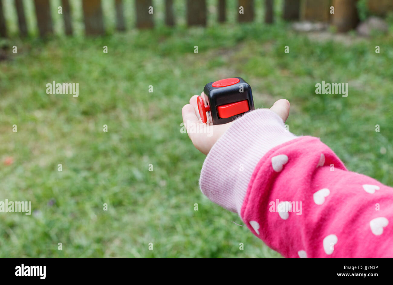 Little blonde girl holding a fidget cube stress relieving object ...