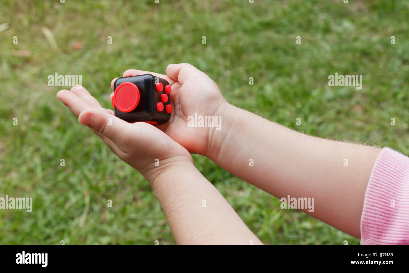 Little blonde girl holding a fidget cube stress relieving object ...