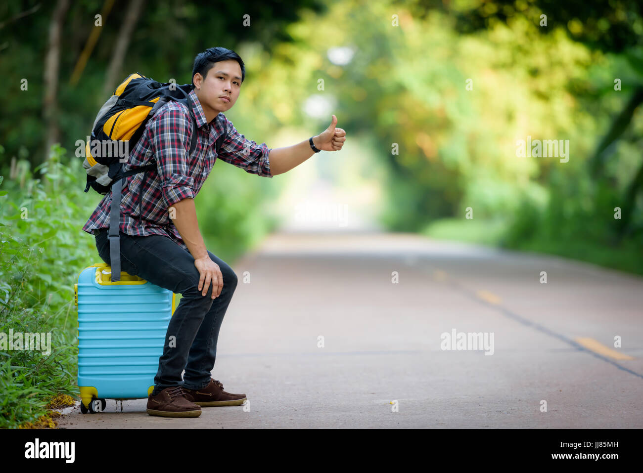 Backpacker is hitchhiking Stock Photo - Alamy