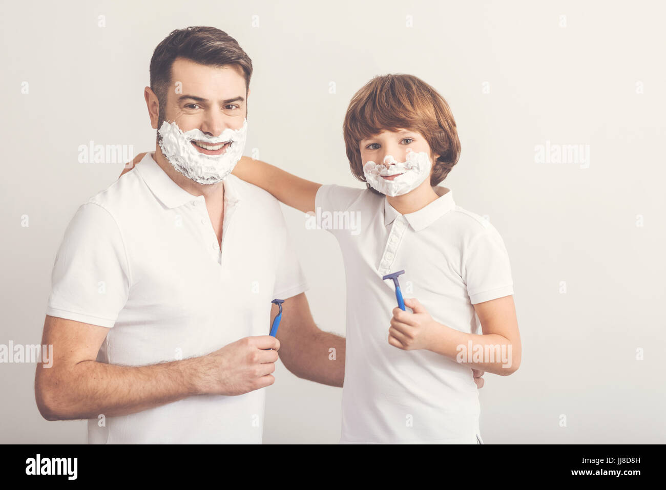 Positive nice father and son holding razors Stock Photo - Alamy