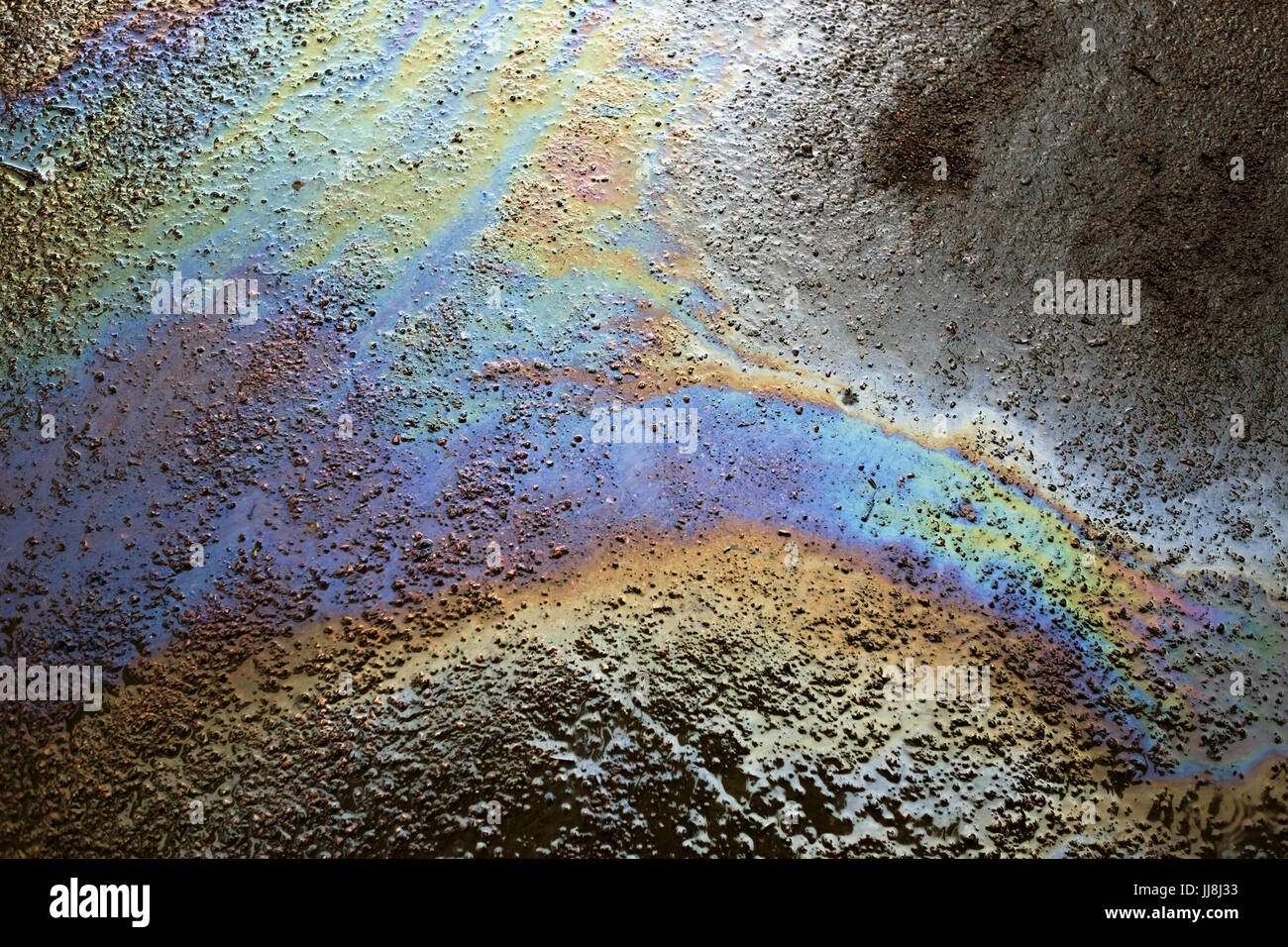 Background texture of an oil spill on road. Environmental pollution ...