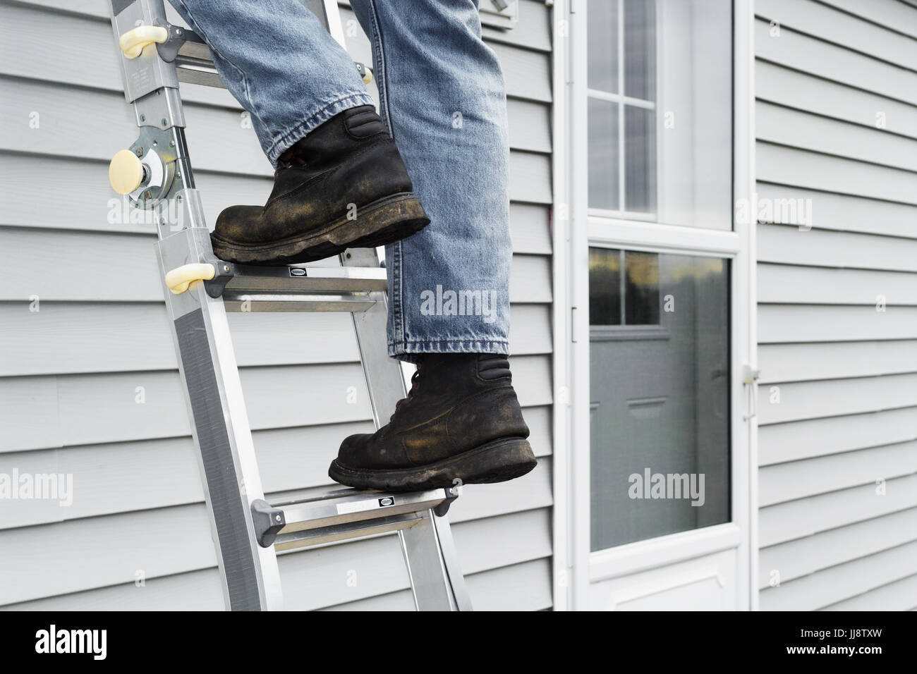 Man climbing ladder with house exterior background Stock Photo - Alamy