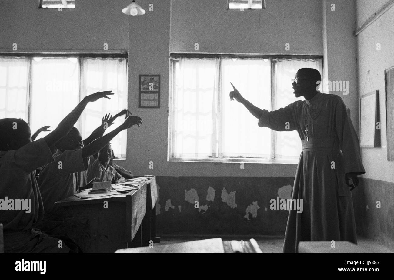 A priest teaching Catholic school in Africa. The location is near Lake ...