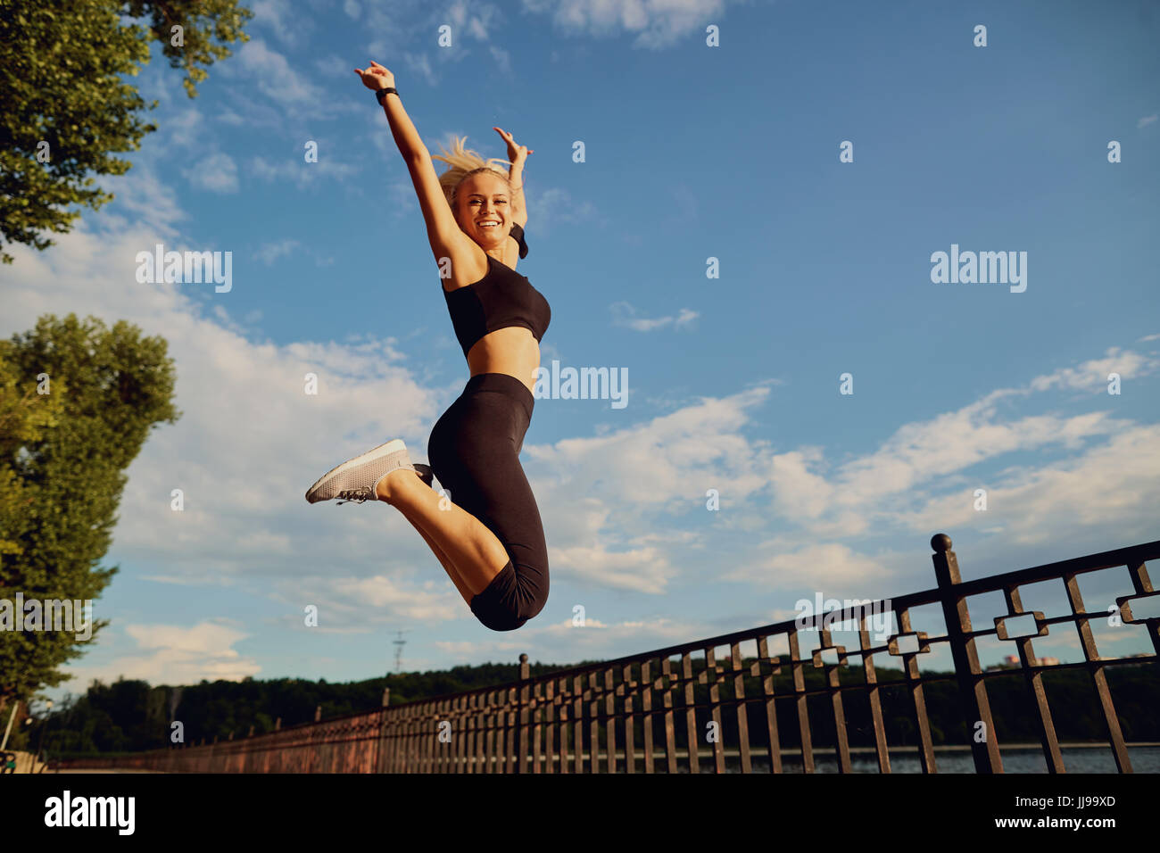 Jumping sports girl on the blue sky Stock Photo - Alamy