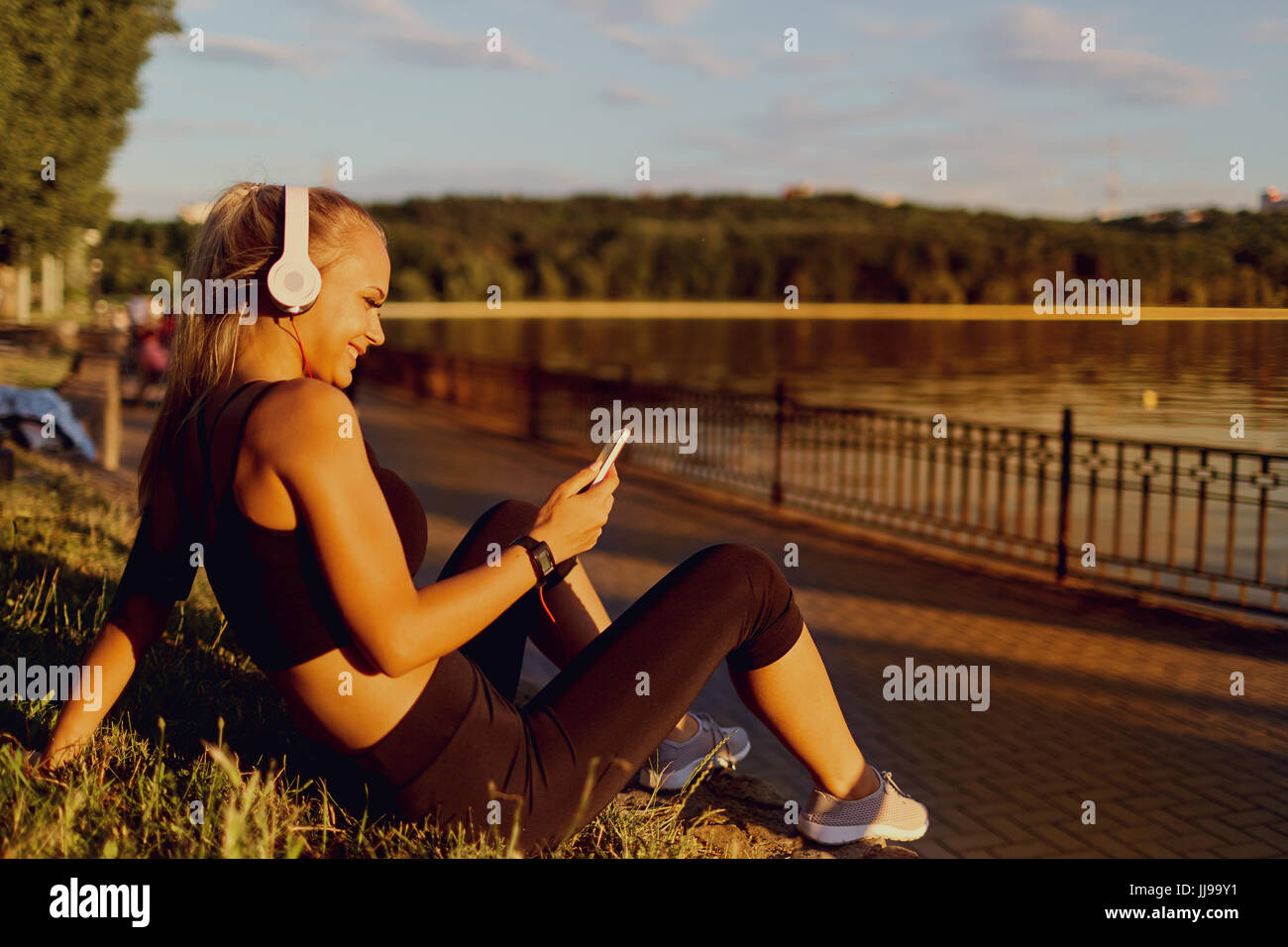 Girl runner listening to music in the park Stock Photo - Alamy