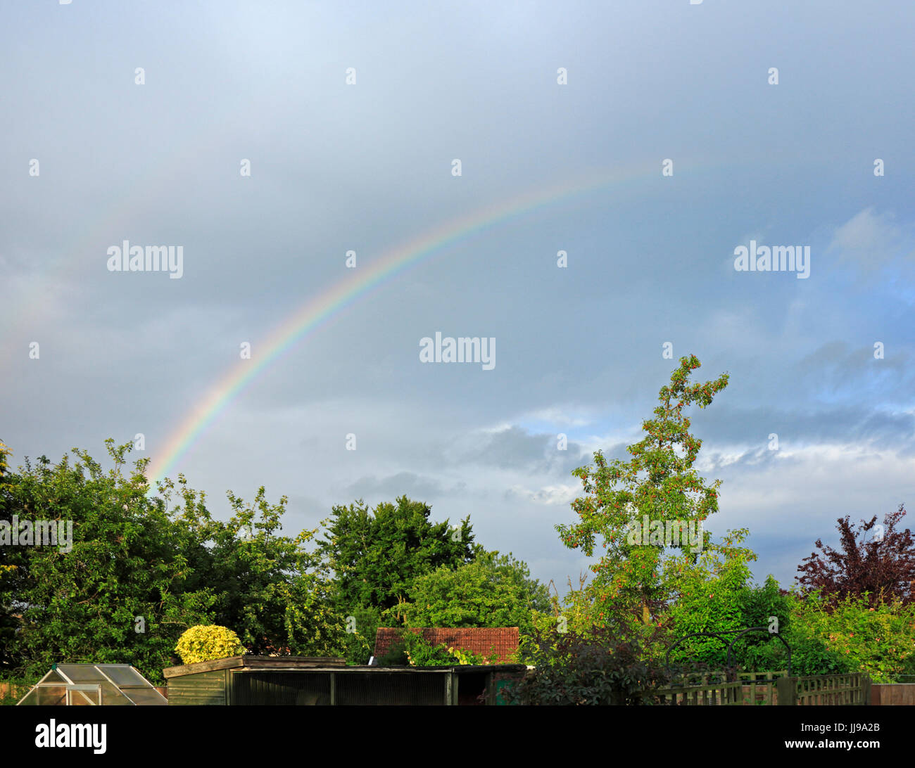 A view of a rainbow over gardens at Hellesdon, Norfolk, England, United ...