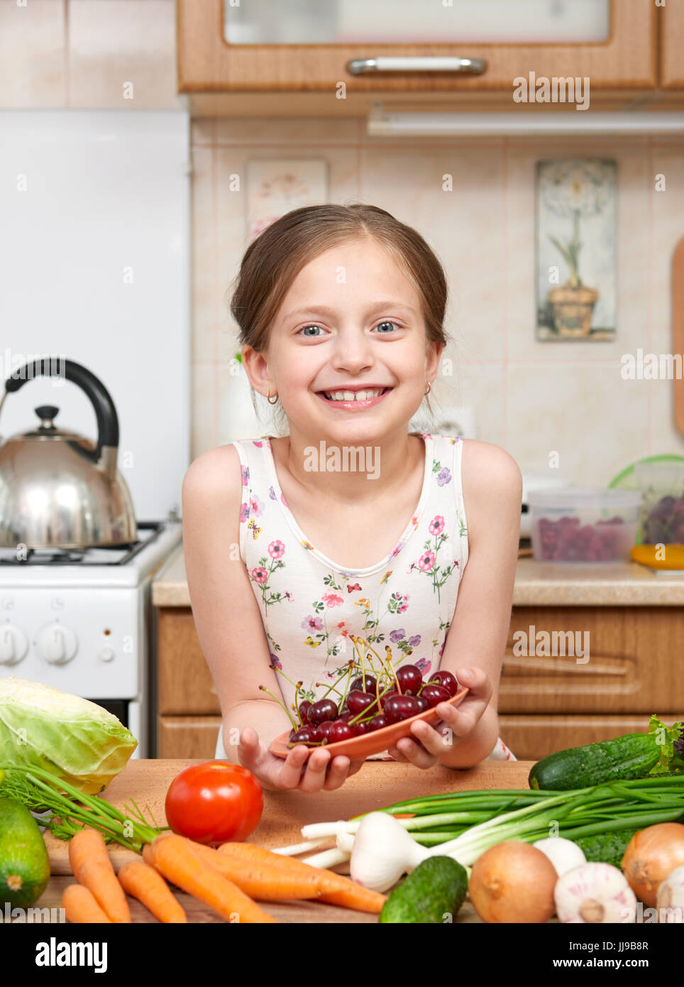 Girl giving a plate of cherries. Many fruits and vegetables on the ...