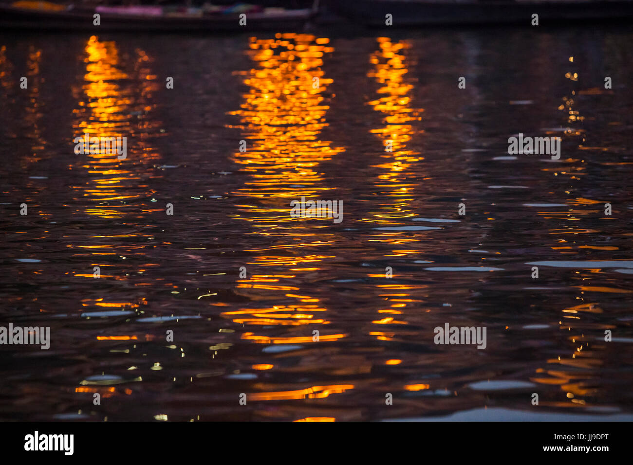 Reflections of the cremation funeral pyres in the Ganges river at night ...