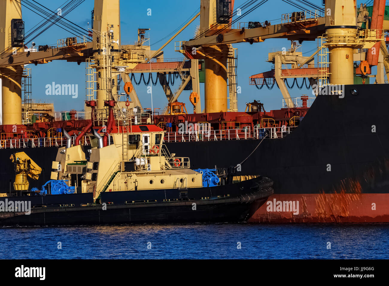 Black cargo ship mooring at the port with tug ship support Stock Photo ...