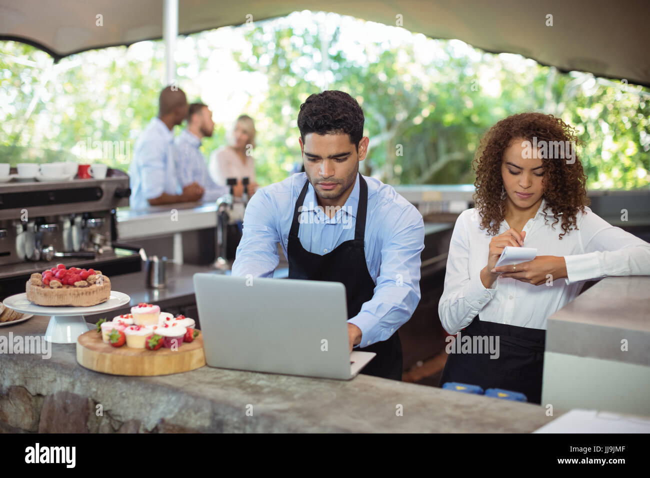 Male waiter and female waitress with laptop at outdoor restaurant Stock ...