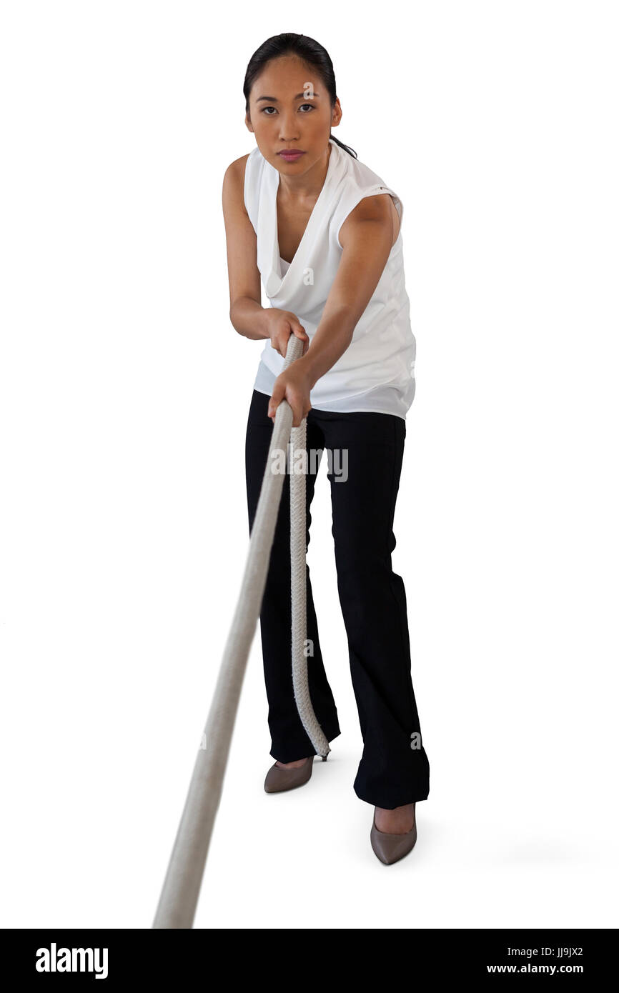 Portrait of young woman pulling rope against white background Stock ...