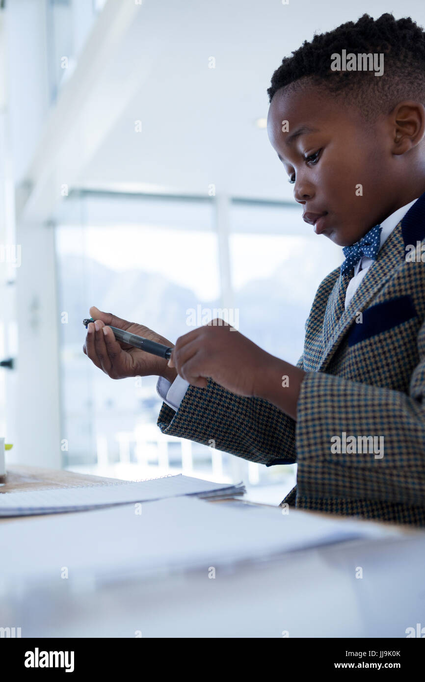 Businessman checking pen while making report at desk in office Stock ...