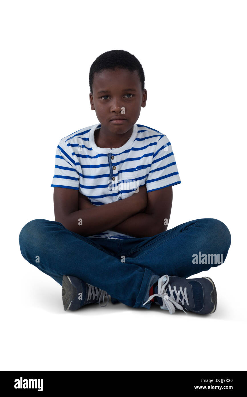 Portrait of sad boy sitting on floor against white background Stock ...