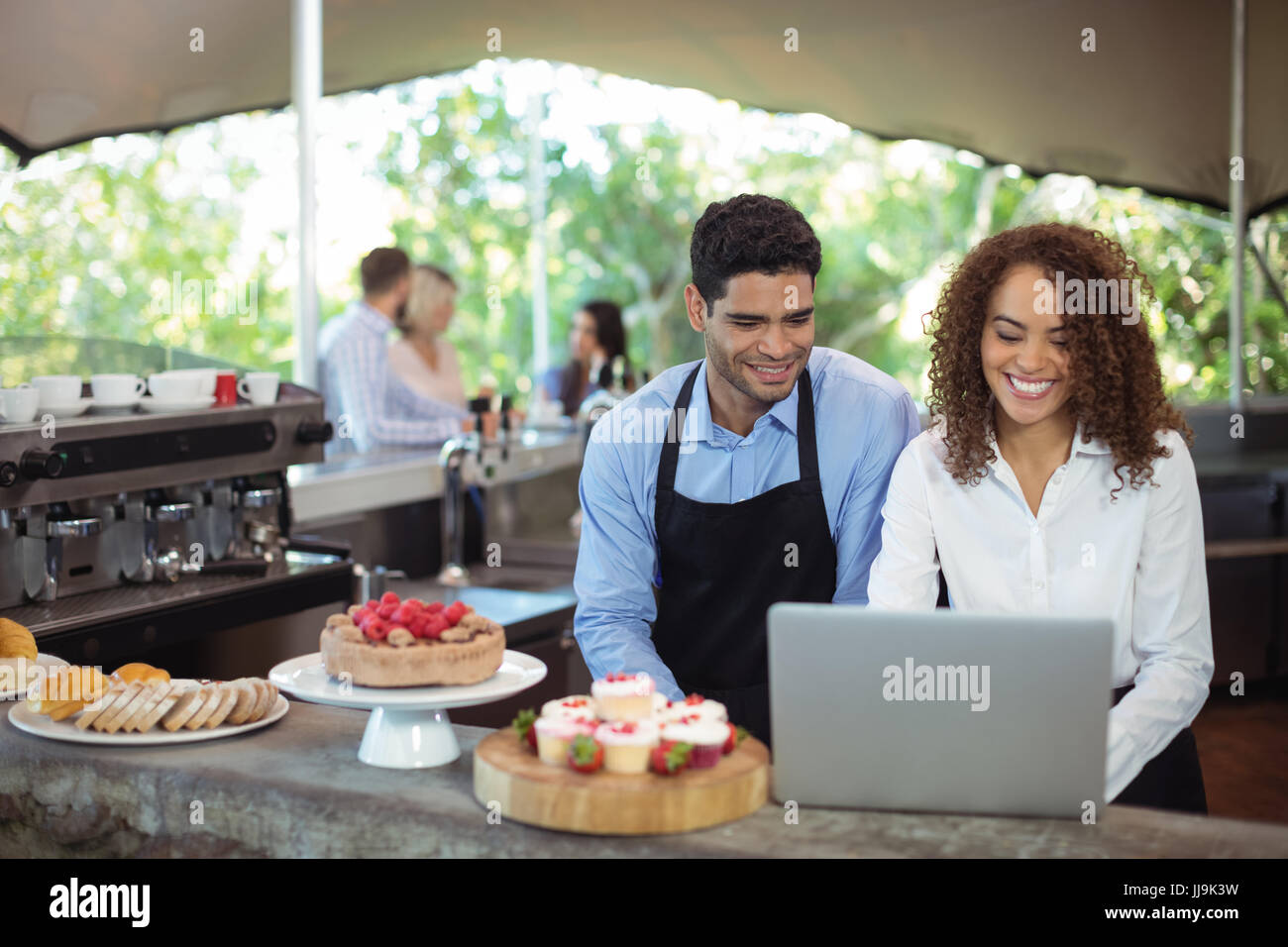 Male waiter and female waitress with laptop at outdoor restaurant Stock ...