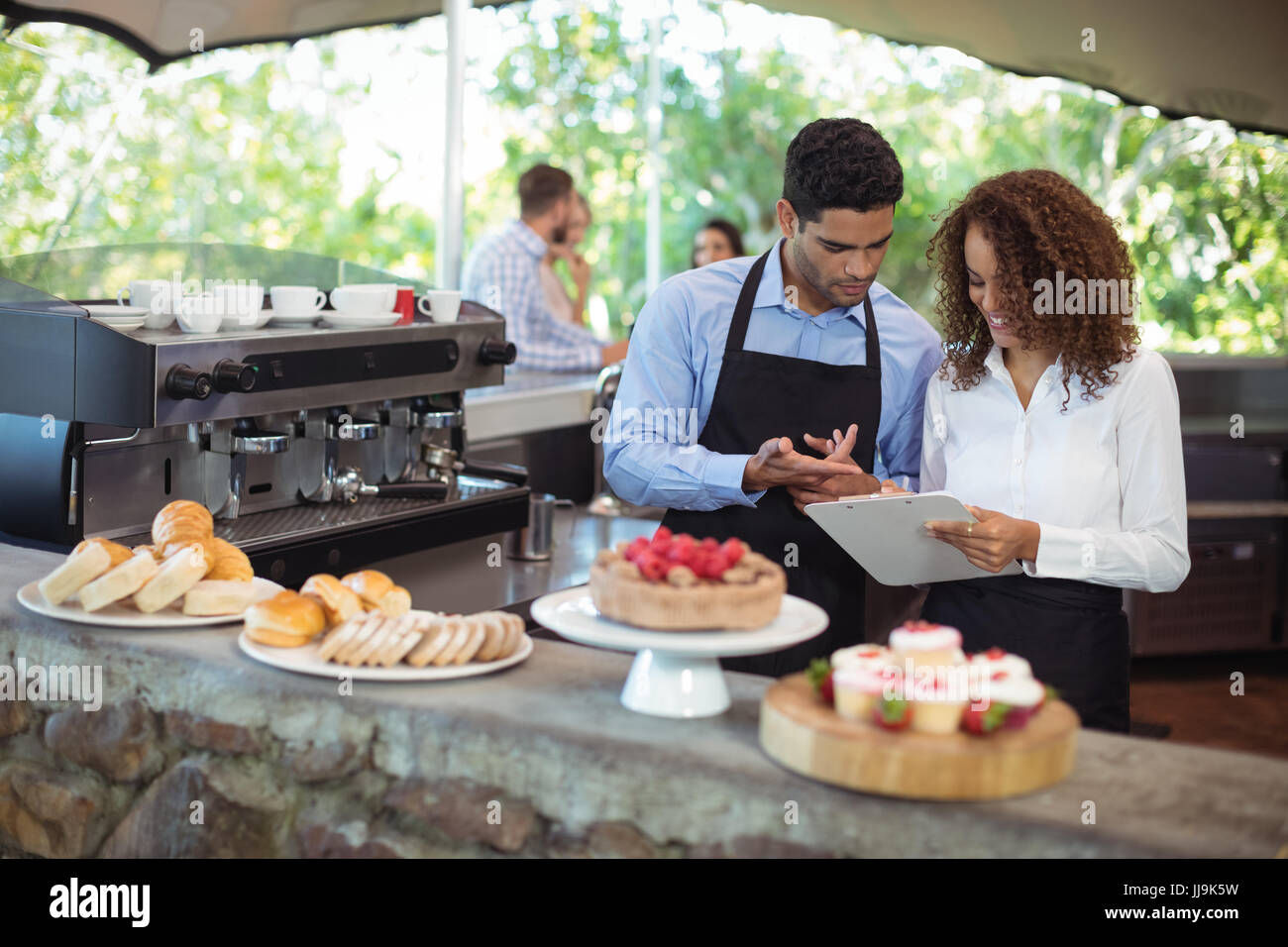 Waiter and waitress discussing on clipboard at counter in restaurant ...