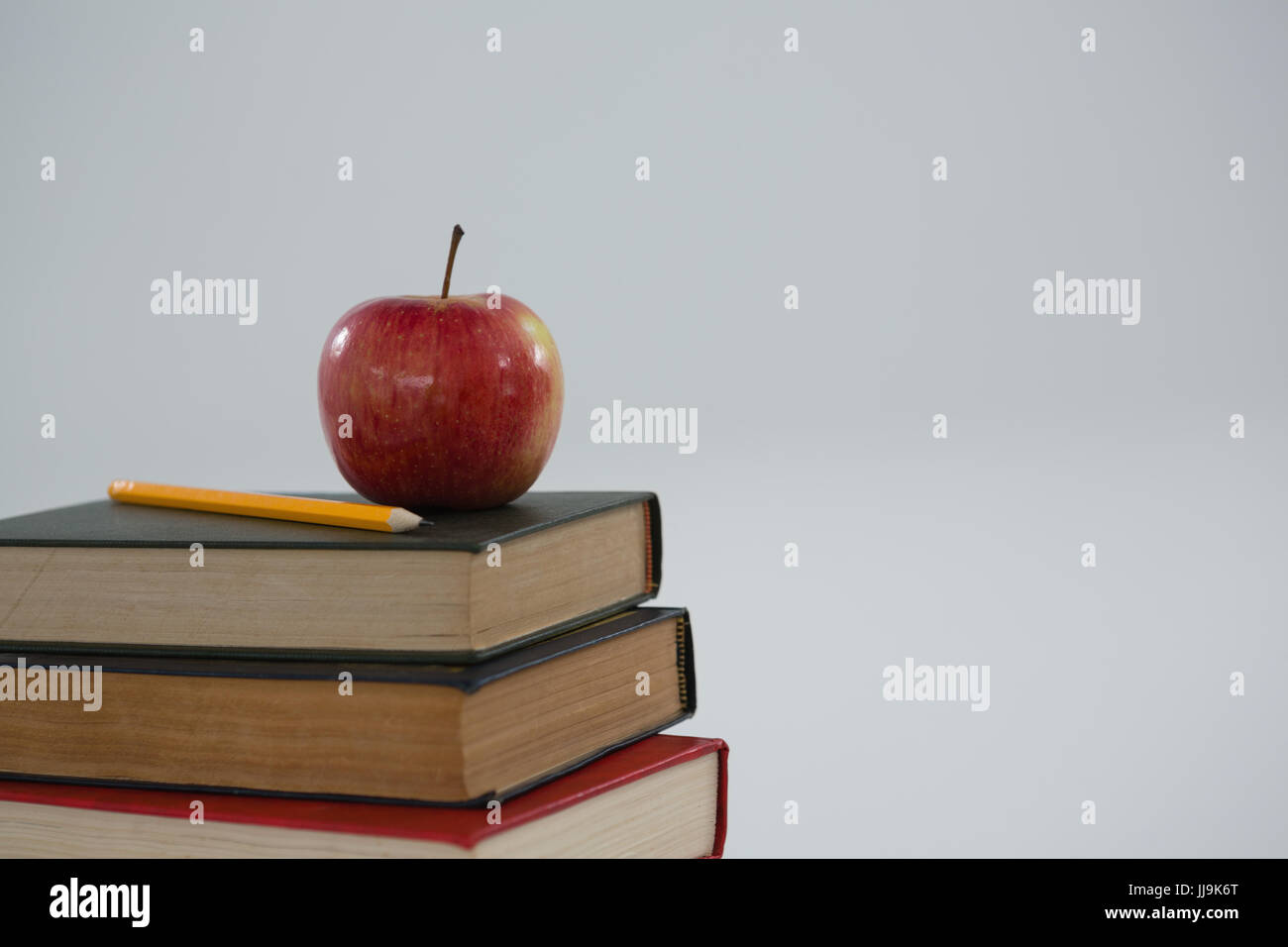 Close-up of apple and pencil on book stack on white background Stock ...