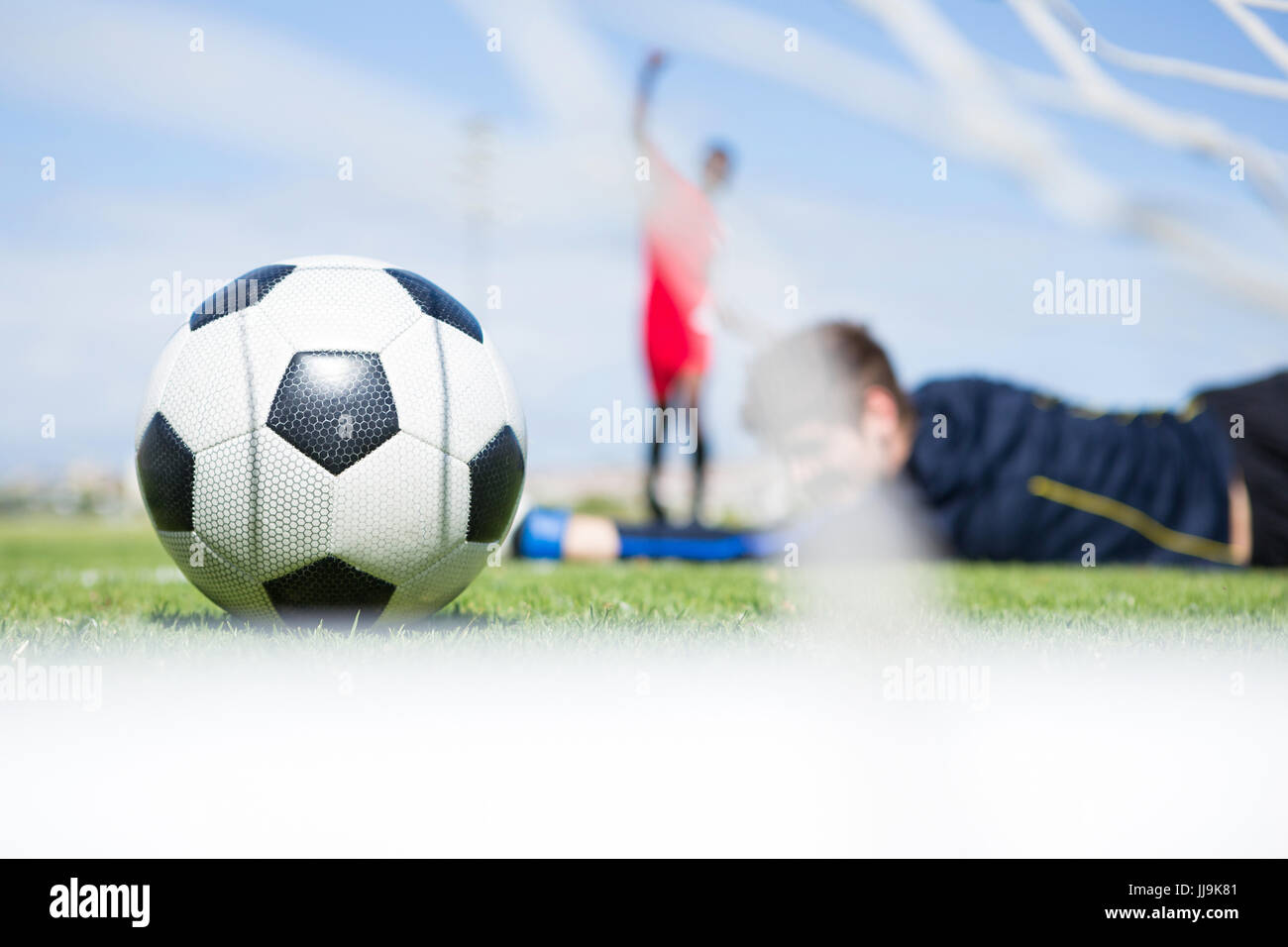 Goalkeeper lying on field while playing soccer against sky Stock Photo ...