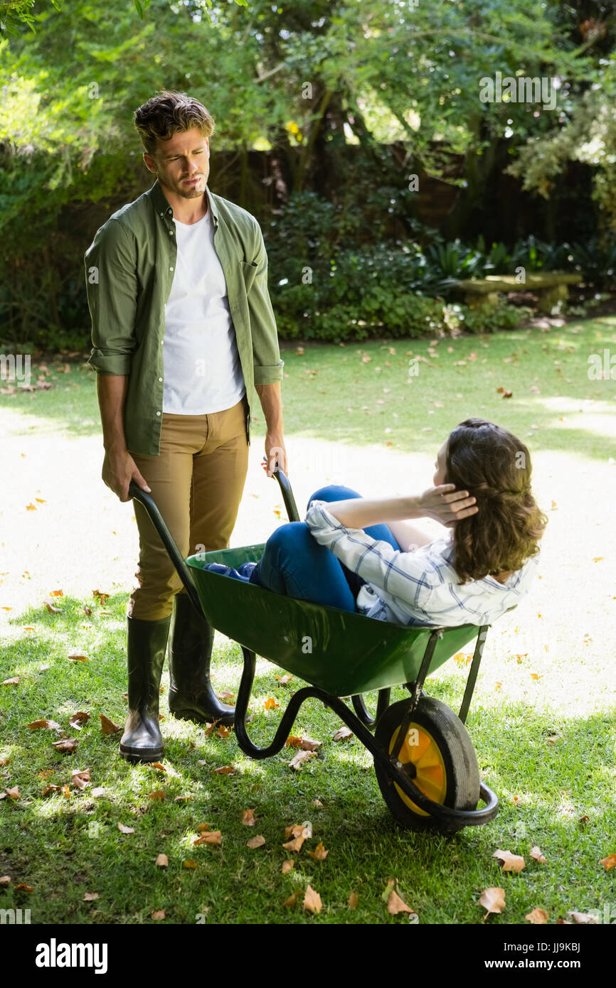 Man interacting with woman while pushing wheelbarrow in garden on a ...