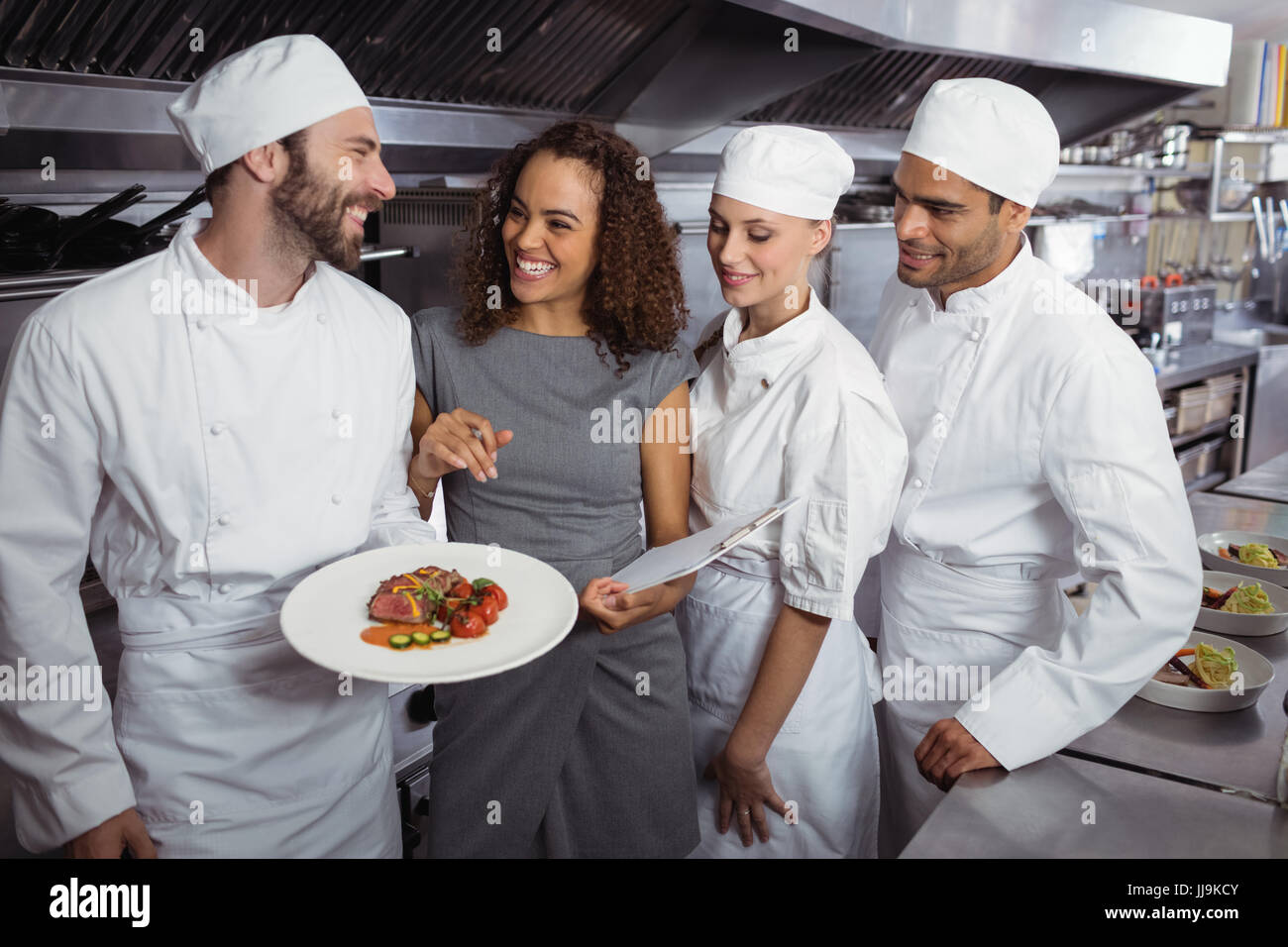 Restaurant manager interacting with his kitchen staff in commercial ...