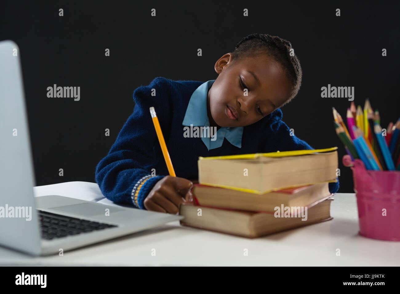 Schoolgirl doing homework against black background Stock Photo - Alamy