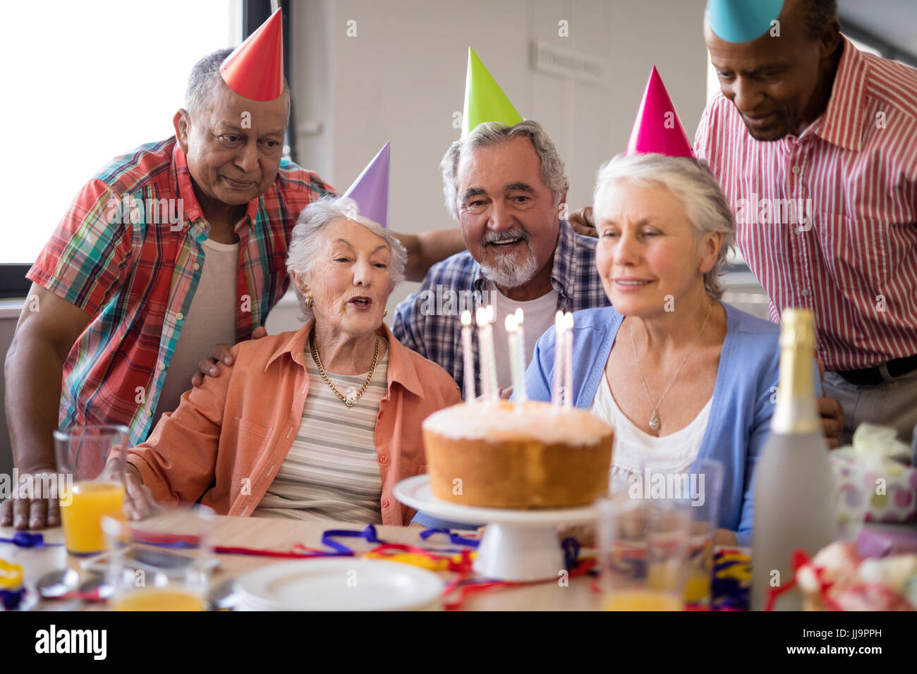 Happy senior people wearing party hats celebrating birthday at nursing ...