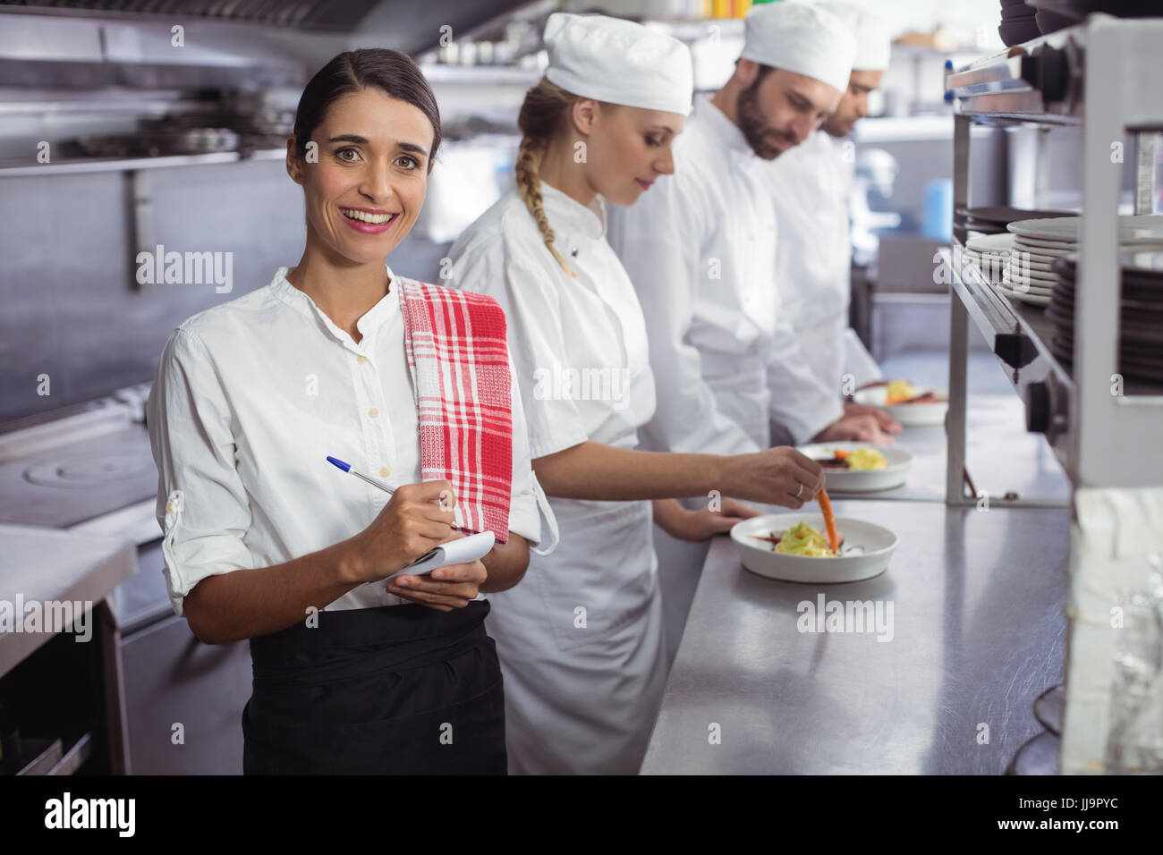 Portrait of waitress standing with notepad in commercial kitchen Stock ...