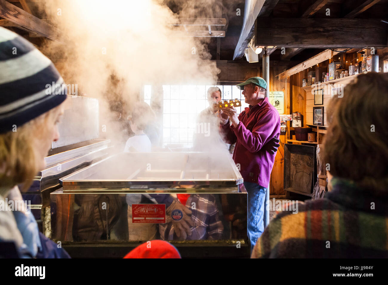A sugarmaker demonstrates the grading of maple syrup to visitors to his ...