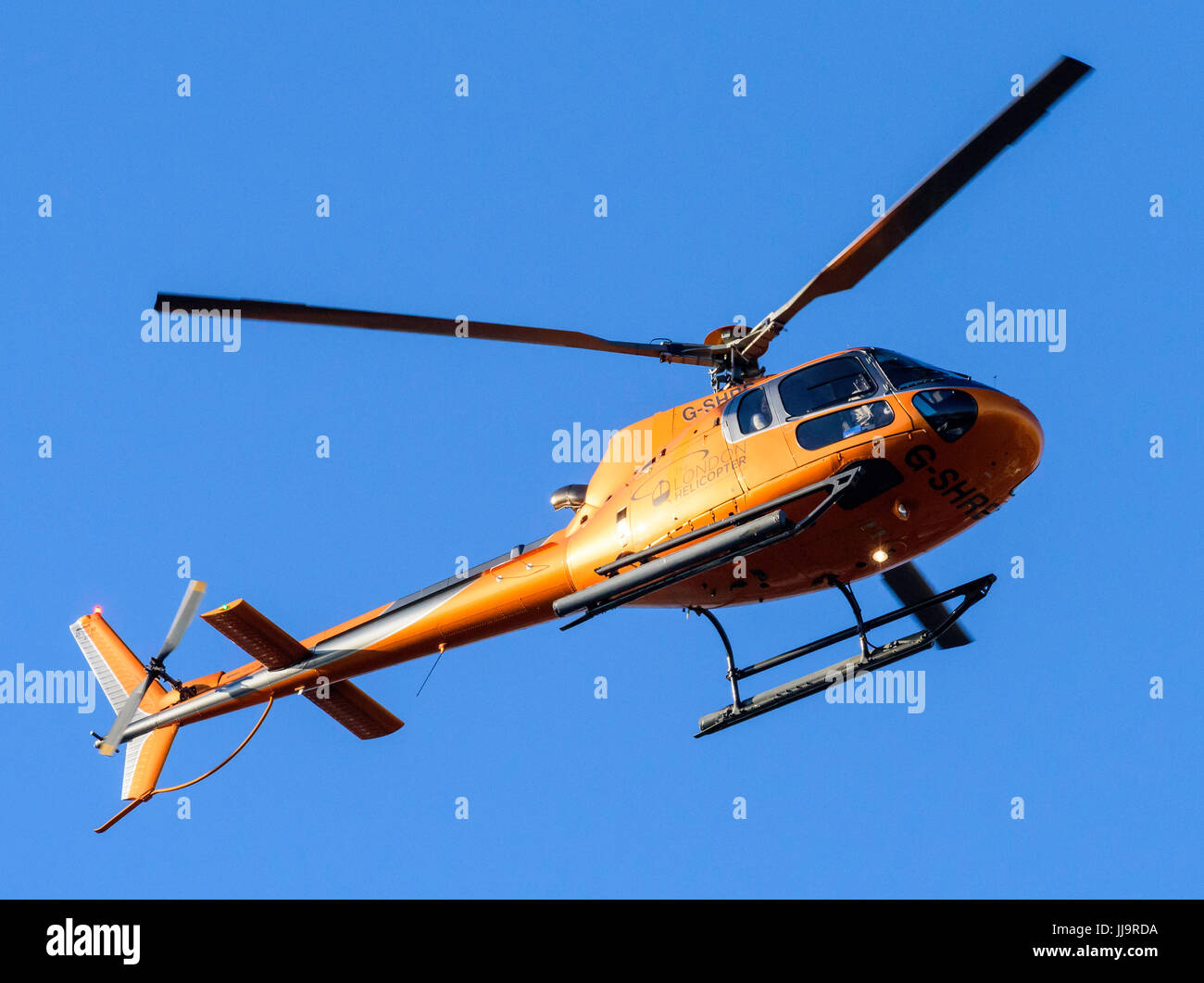 Orange helicopter in blue sky Stock Photo - Alamy