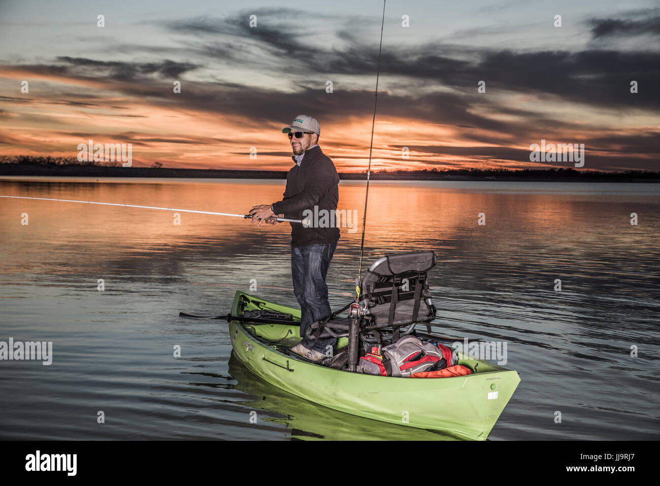 Fishing man standing in canoe Stock Photo - Alamy