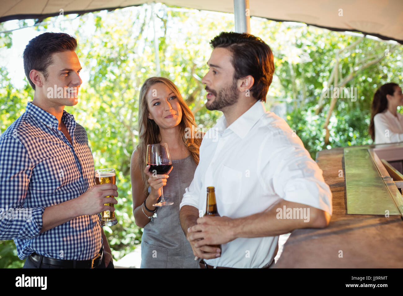 Smiling friends interacting while having a alcohol at counter Stock ...