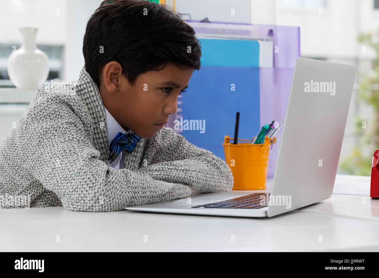 Side view of businessman looking at laptop computer while sitting at ...