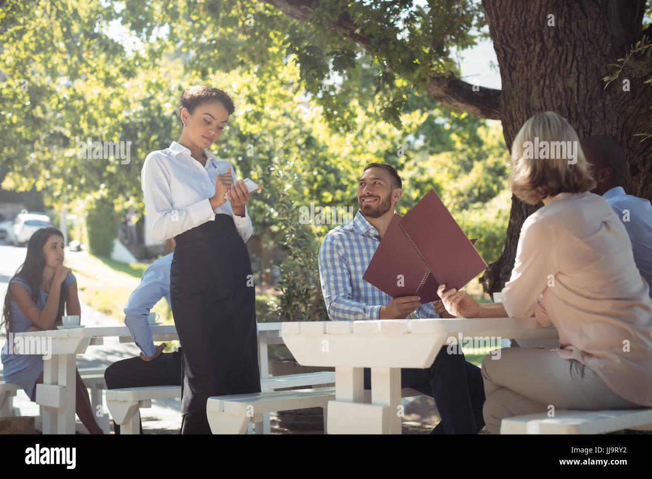 Waitress taking order from customer in the restaurant on a sunny day ...
