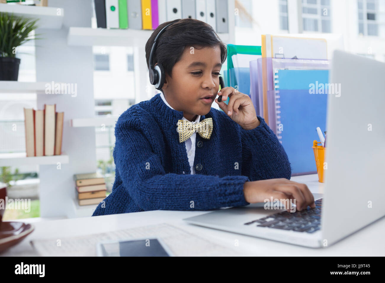 Businessman talking on microphone with head set while working on laptop ...