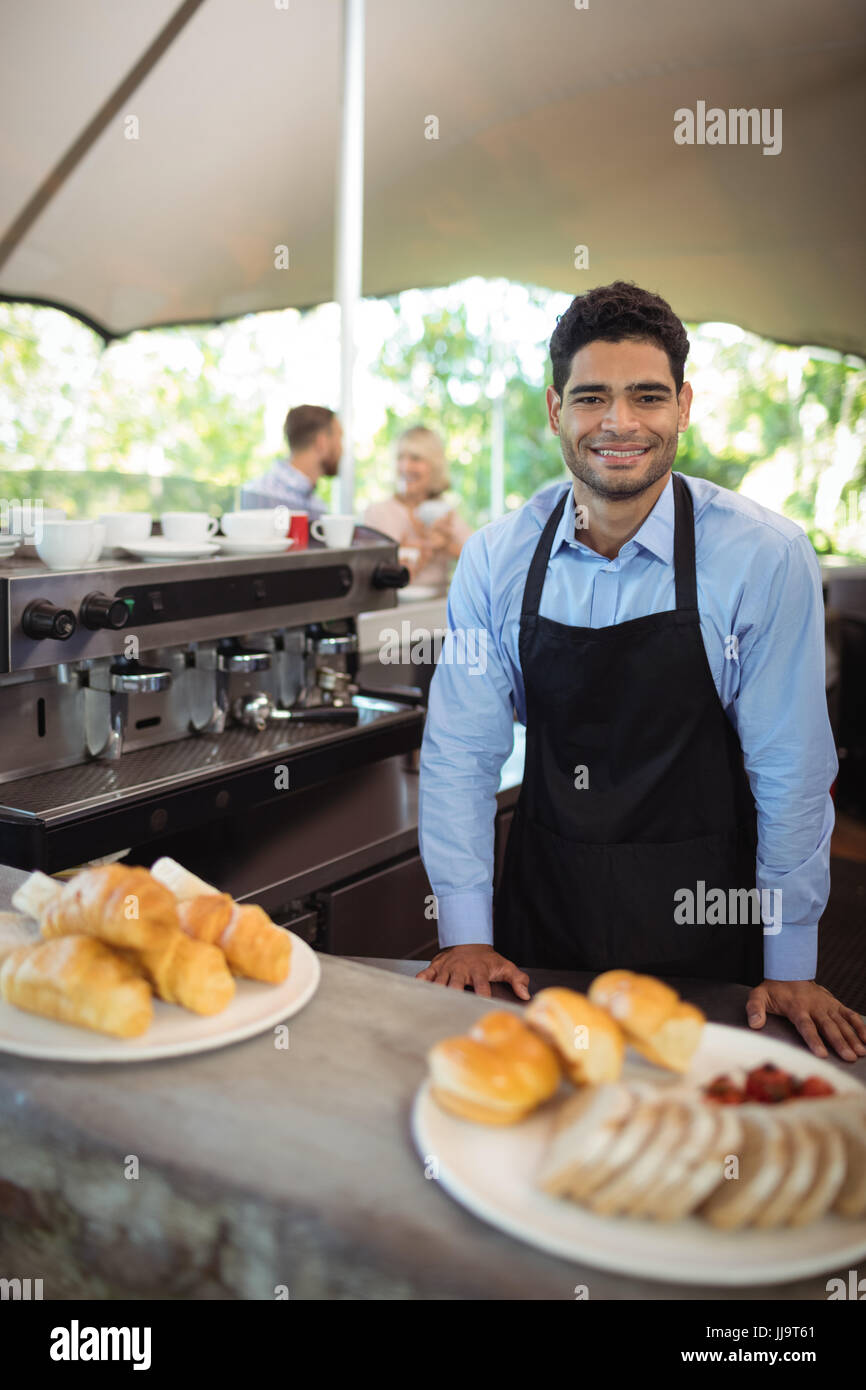 Portrait of smiling waiter standing near counter at restaurant Stock ...