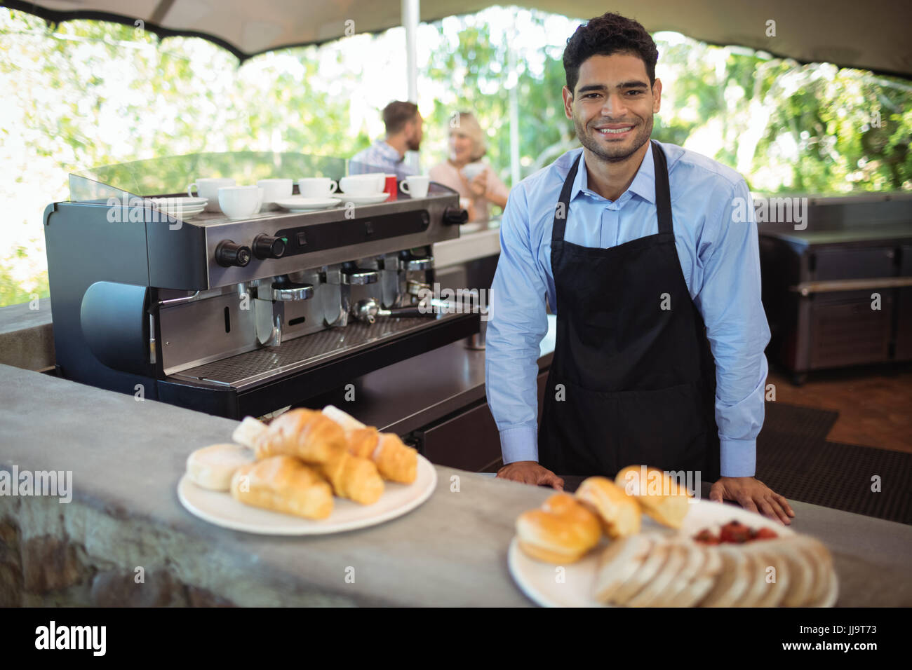 Portrait of smiling waiter standing near counter at restaurant Stock ...