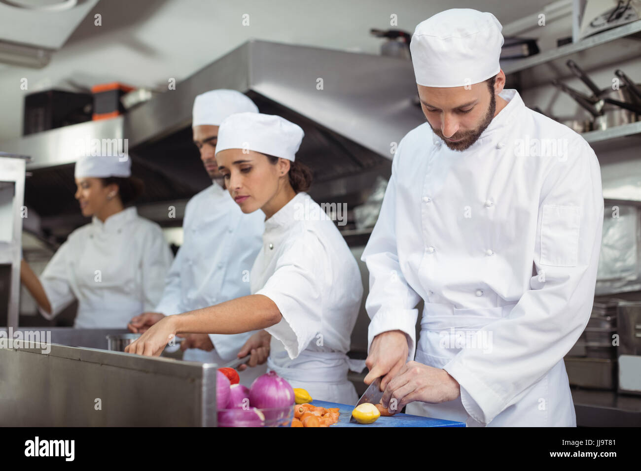 Chefs chopping vegetables on chopping board in the commercial kitchen ...